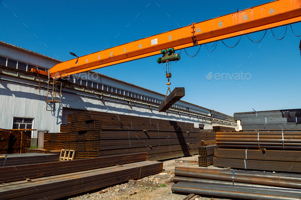Gantry crane transporting stack of metal pipes Stock Photo by collab_media