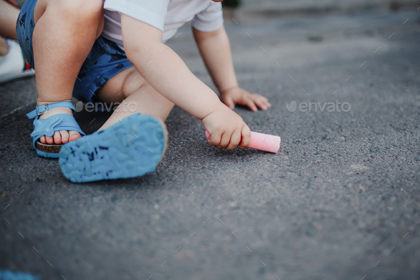 Close up of little girl drawing with chalks on the sidewalk. Kids ...