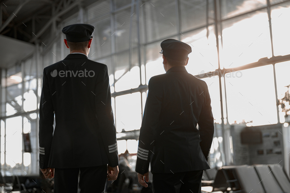 Two male pilots standing in airport terminal Stock Photo by friends_stock