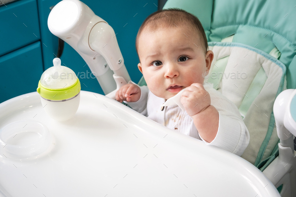 The baby eats from a bottle at the feeding table. Introduction of ...