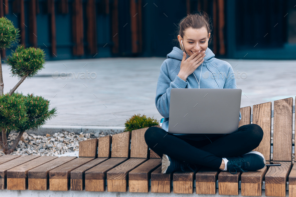 Pretty girl holding laptop outdoors, smiling. Stock Photo by tymoshchukph