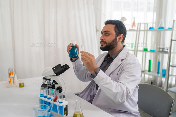 Lab Worker Using Magnifying Glass on Microscope Stock Photo by FoToArtist_1