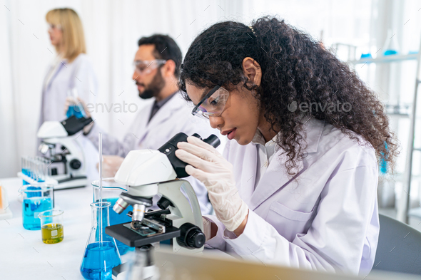Lab Worker Using Magnifying Glass on Microscope Stock Photo by FoToArtist_1