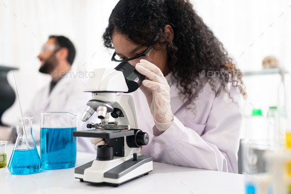 Lab Worker Using Magnifying Glass on Microscope Stock Photo by FoToArtist_1