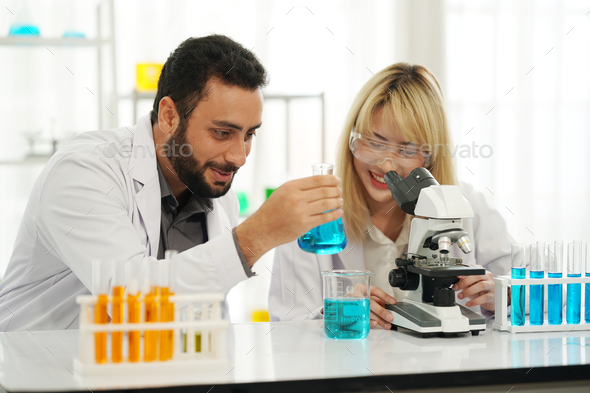 Lab Worker Using Magnifying Glass on Microscope Stock Photo by FoToArtist_1