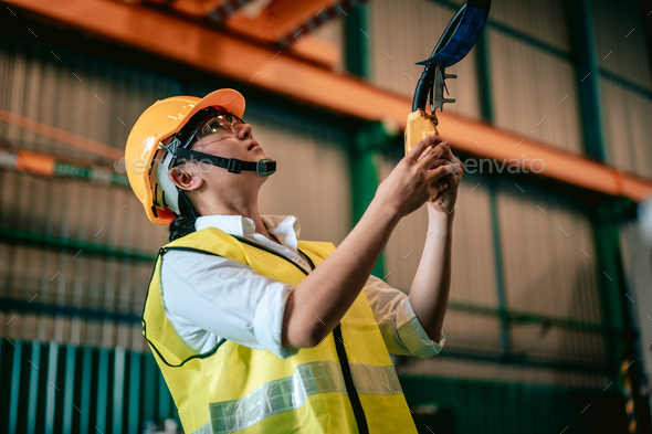 Asian woman engineer uses remote control panel to lift up or down of ...