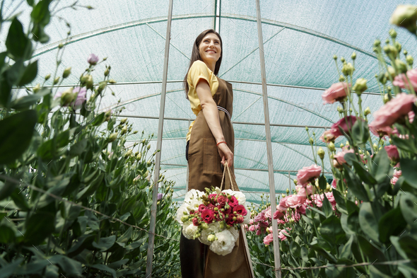 Flower cultivation business, woman walking through green house to see ...
