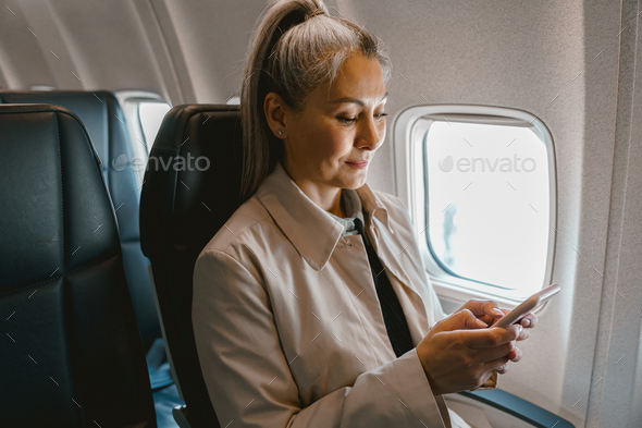 Beautiful Asian woman passenger sitting in the airplane and use phone during boarding Stock ...