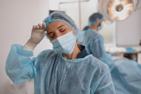 Close up of tired surgeon in mask standing in operating room after ...