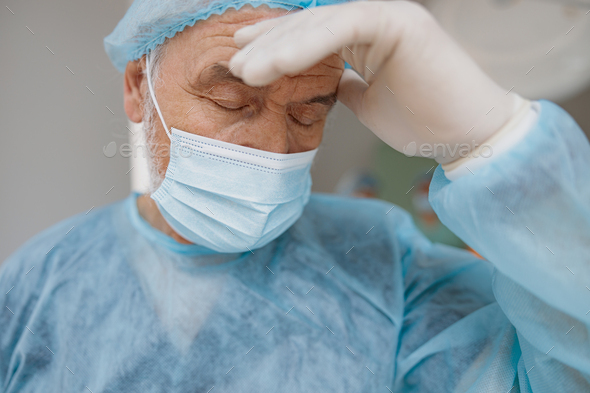 Close up of tired surgeon in mask standing in operating room after ...