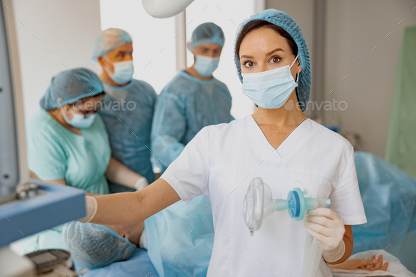 Nurse holding breathing mask for anesthesia standing in operation room ...