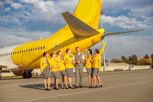 Airline workers standing near yellow aircraft at airfield Stock Photo ...