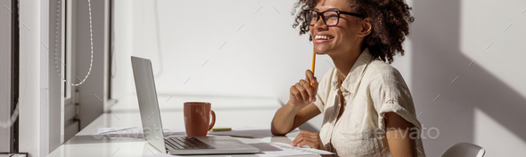 Smiling businesswoman working and looking out the window in the office ...