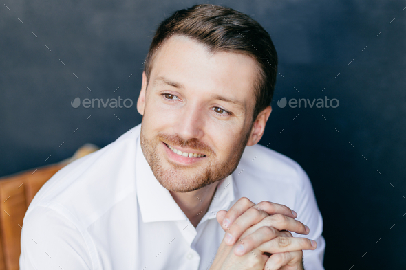 Indoor shot of handsome unshaven male with charming smile, wears ...