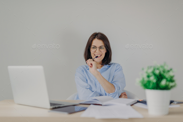 Intelligent gorgeous female dressed casually works at home, sits in ...