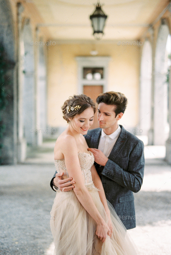 Bride and groom are hugging on the terrace with arches. Lake Como ...