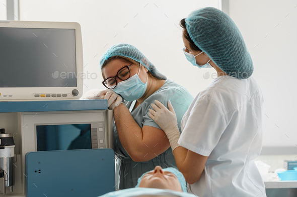 Tired nurses after difficult operation support each other in operating ...