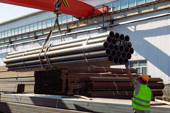 Worker transporting stack of metal pipes with gantry crane Stock Photo ...