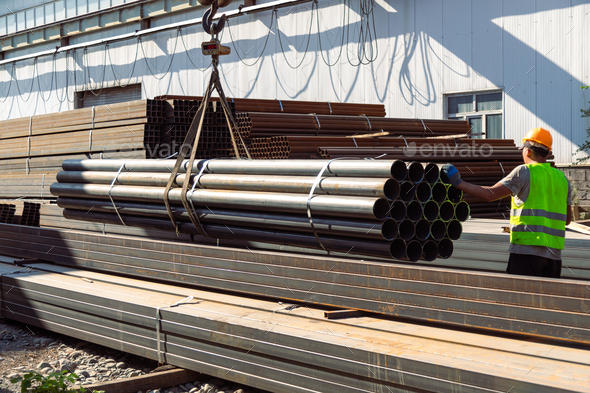 Worker transporting stack of metal pipes with gantry crane Stock Photo ...