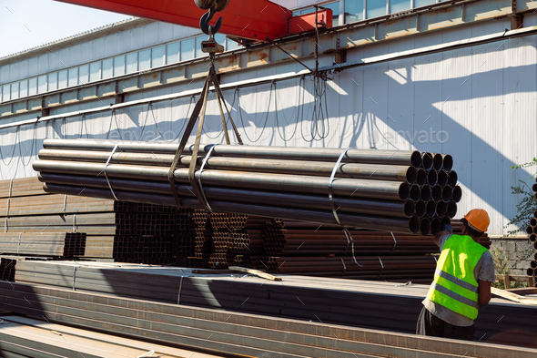 Worker transporting stack of metal pipes with gantry crane Stock Photo ...