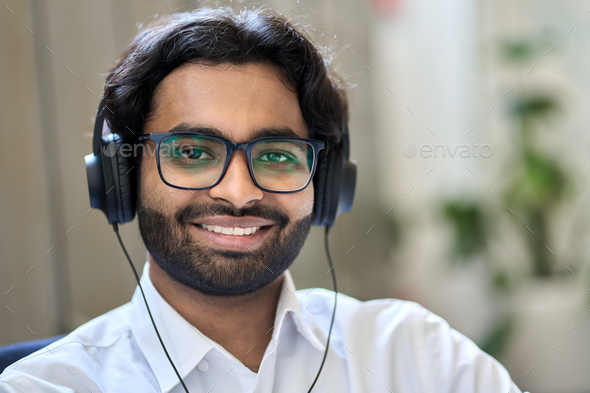 Smiling indian business man wears headphones looks at camera, headshot ...