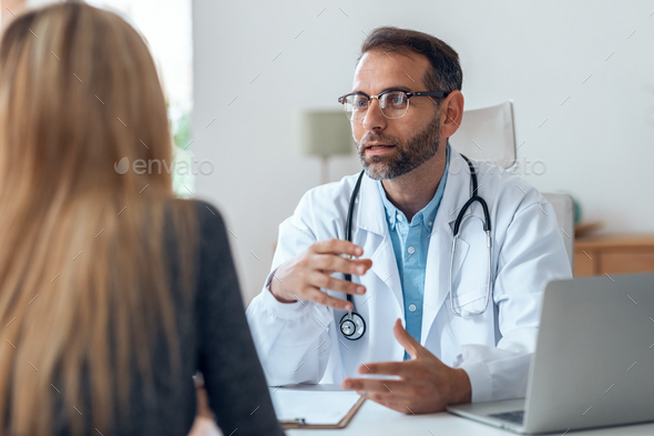 Handsome male doctor explaining medical treatment to patient in the ...