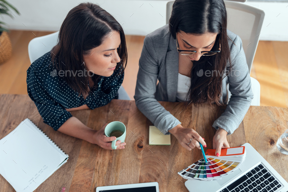 Two beautiful designer women working in a design project while choosing ...