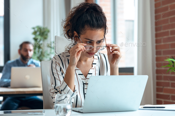 Tired business woman with headache looking uncomfortable while working ...