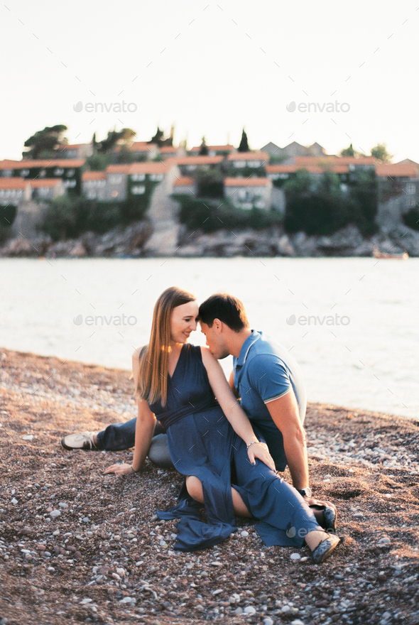 Man kisses woman shoulder on the beach overlooking the island of Sveti ...