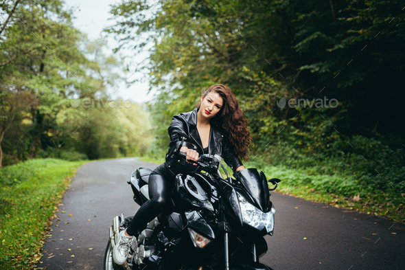 Portrait of a beautiful young woman sitting on a motorcycle, riding a ...