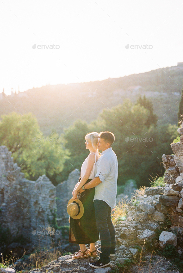 Man hugs woman from behind in the ruins of a castle. Side view Stock ...