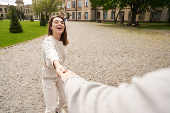 Cheerful woman pulling man hand on the street Stock Photo by svitlanah
