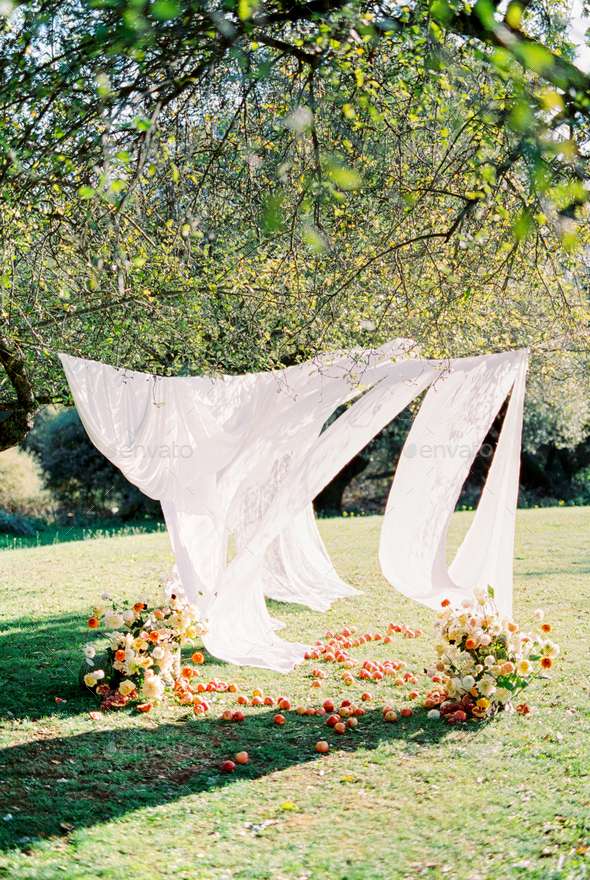 White curtains flutter over apples and flower bouquets in the garden ...