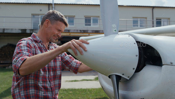 Aviator fixing airplane propeller smiling enjoying preflight process ...