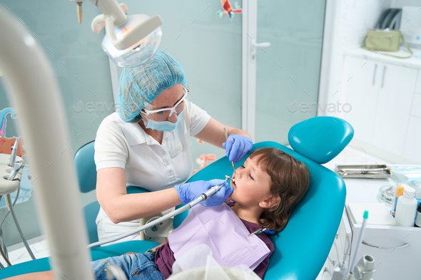 Professional pedodontist is performing teeth-polishing procedure on ...