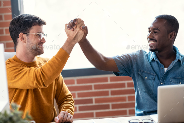 Two graphic designer while celebrating something shaking hands in ...