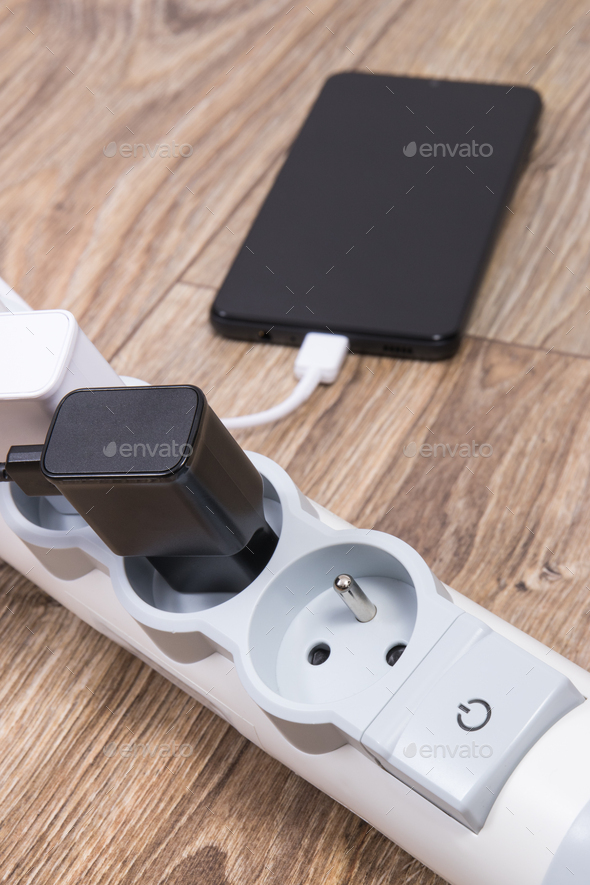 Smartphone and chargers connected to electrical power strip. Various ...
