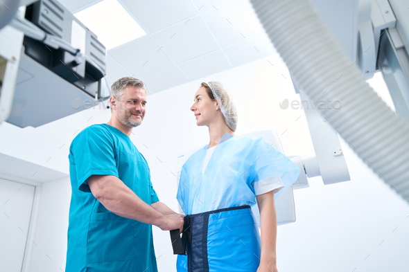 Radiologist at medical center putting lead shield on female patient ...