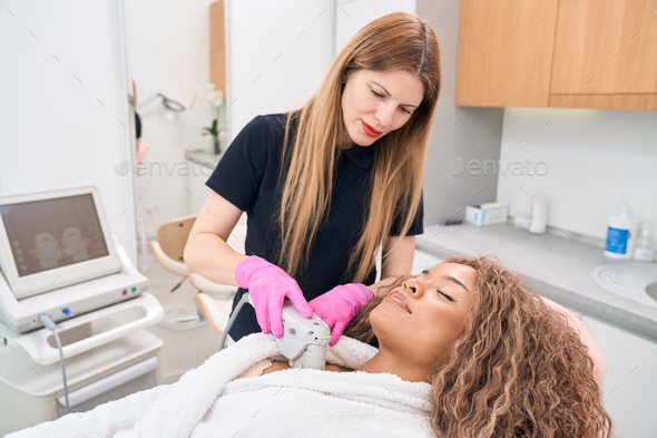 Cosmetologist performs a smas-lifting procedure on the decollete area ...