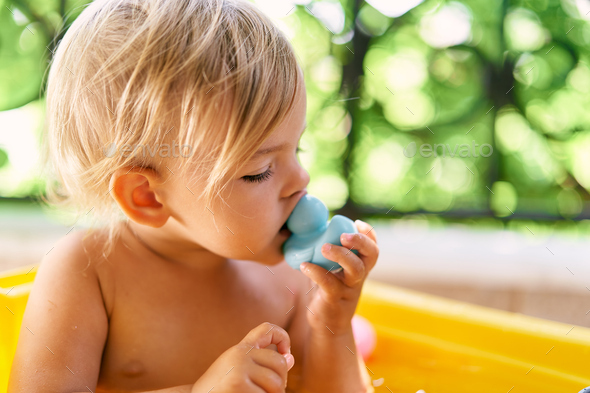 Little kid chews a rubber duck while holding it with his hand Stock ...