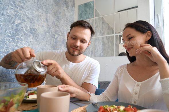 Romantic partner pouring tea from teapot for his wife Stock Photo by ...