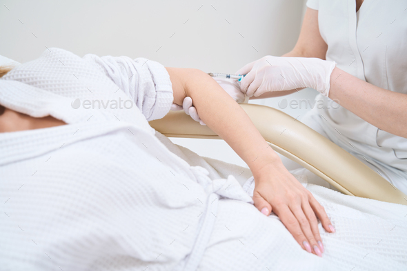 Medical worker gives an injection to a patient to tighten the skin of ...