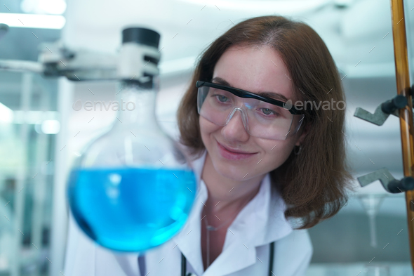 Young scientist in white lab coat working with binocular microscope in ...