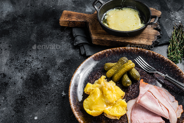 Raclette Melted cheese with boiled potato and ham on rustic plate ...