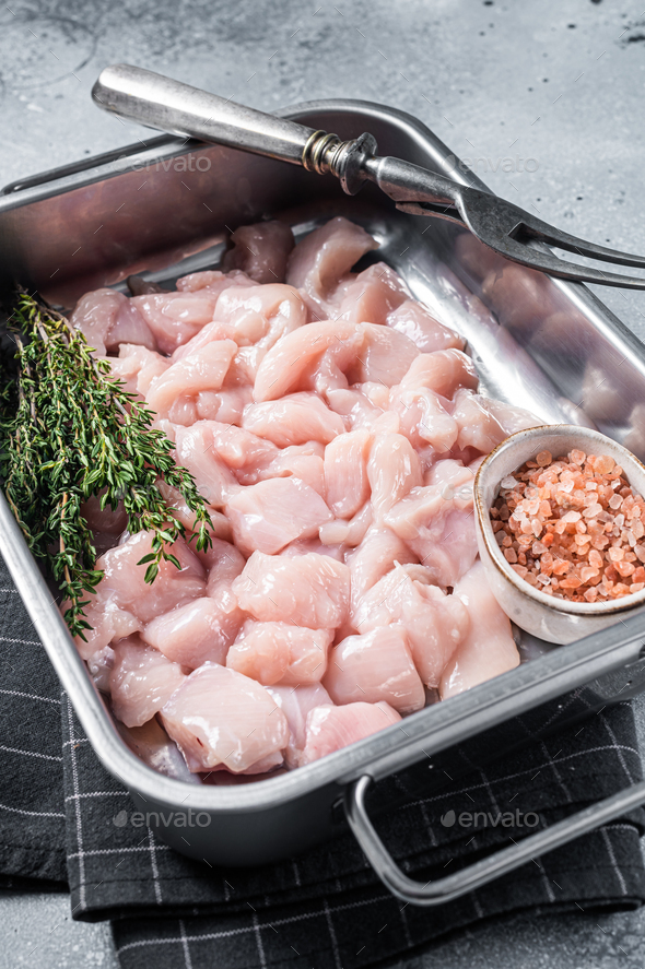 Diced raw chicken breast fillets in steel tray. Gray background. Top ...