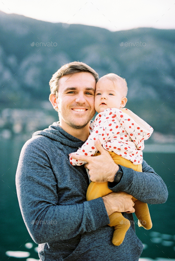 Smiling dad hugs the baby in his arms. Portrait Stock Photo by Nadtochii