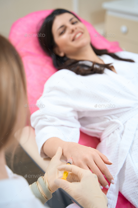 Doctor makes an injection in the hand of the patient to rejuvenate the ...