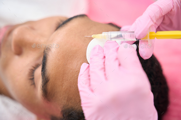 Man receiving forehead filler injection in beauty salon Stock Photo by ...