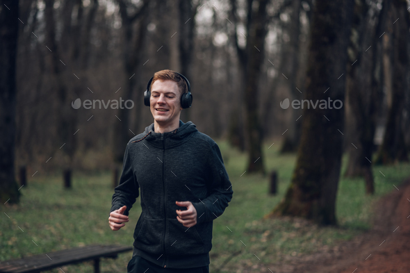 Young redhead man running in forest Stock Photo by zamrznutitonovi