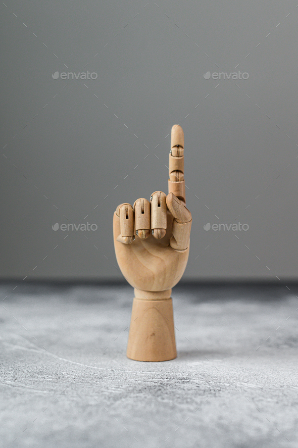 Wooden hand is showing a single raised finger. The concept of ...